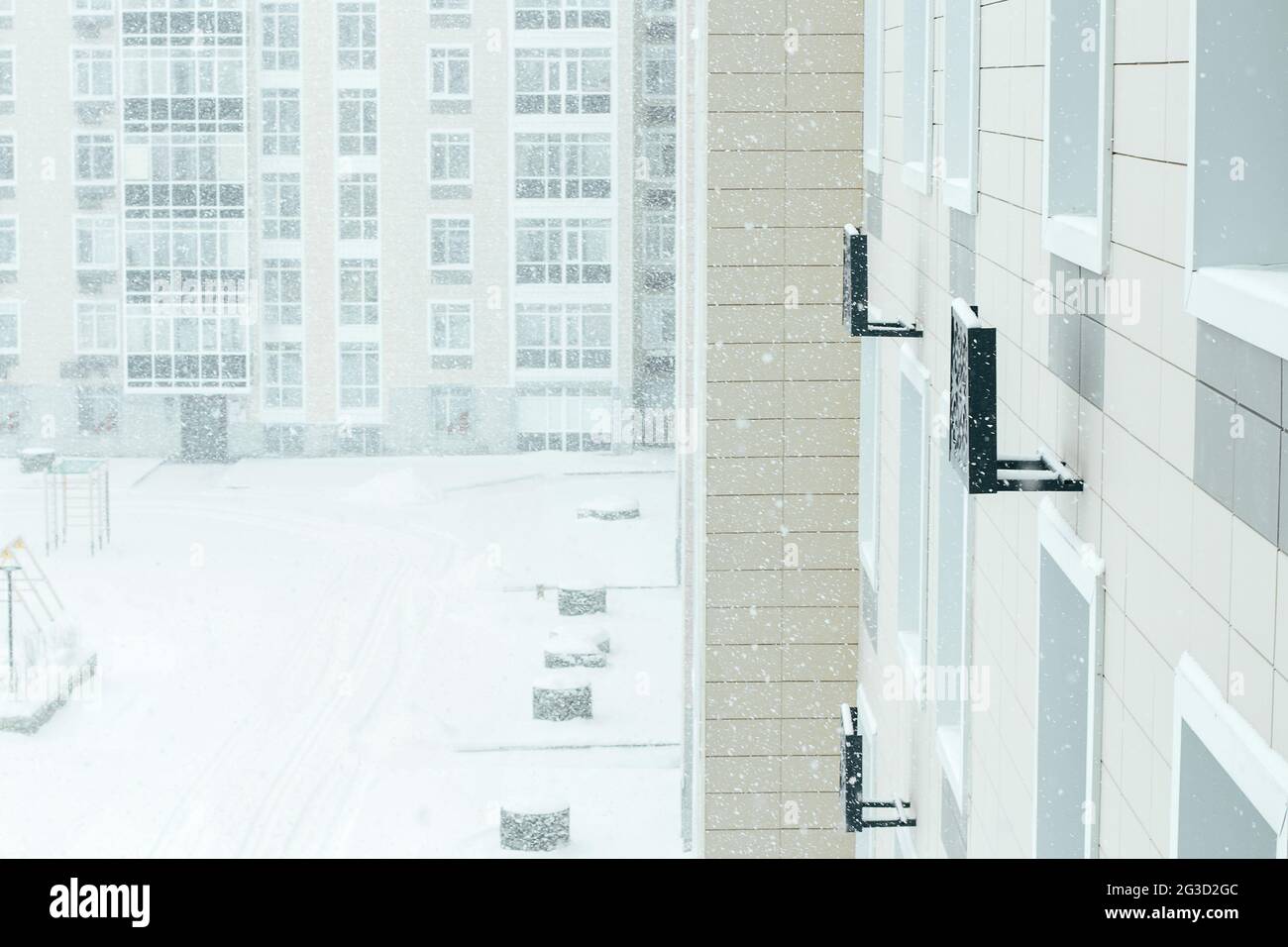 Snowstorm in the city. The yard of a residential building is covered ...