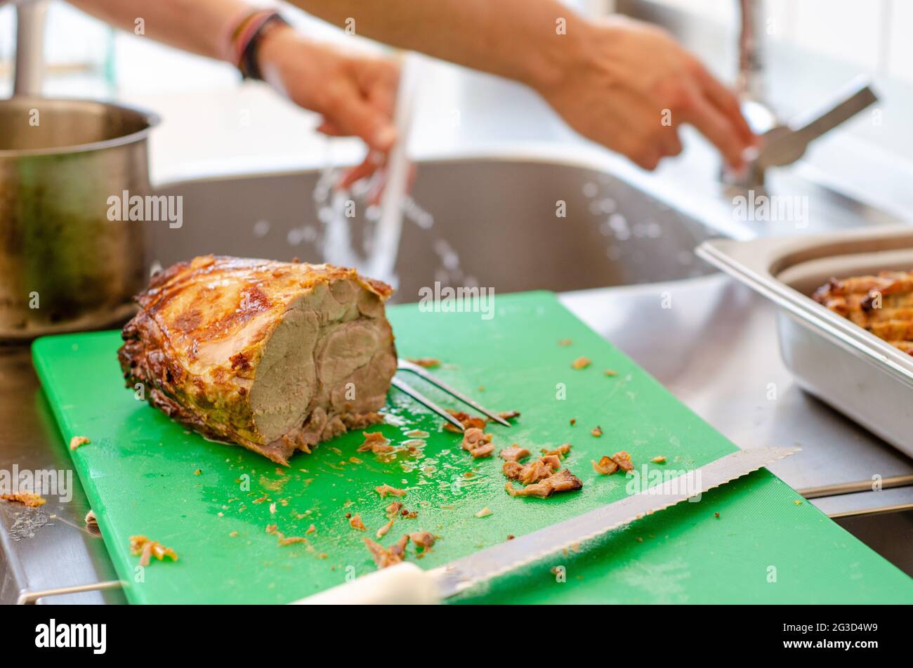 Pork tenderloin on the cutting board; a blurry view of chef washing ...