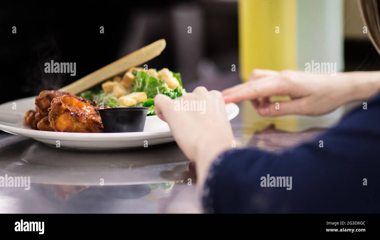 Selective focus of a cook serving fresh salad and cooked meat on a ...