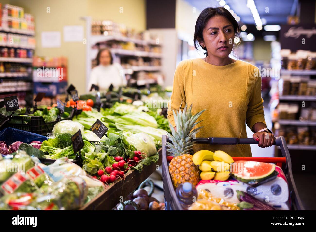Hispanic woman walking with shopping trolley in grocery shop Stock ...