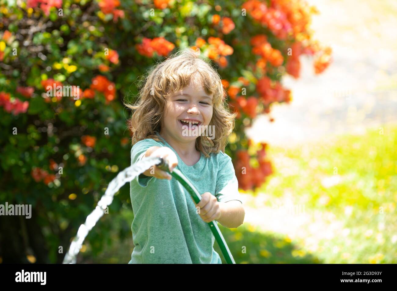 Adorable little boy is watering the plant outside the house, concept of ...