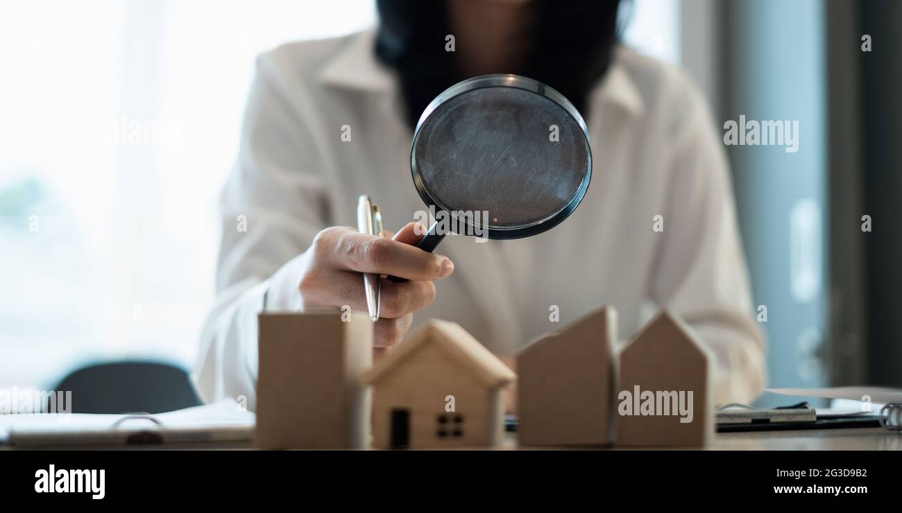 A woman holding magnifying glass and checking house model .Real Estate ...
