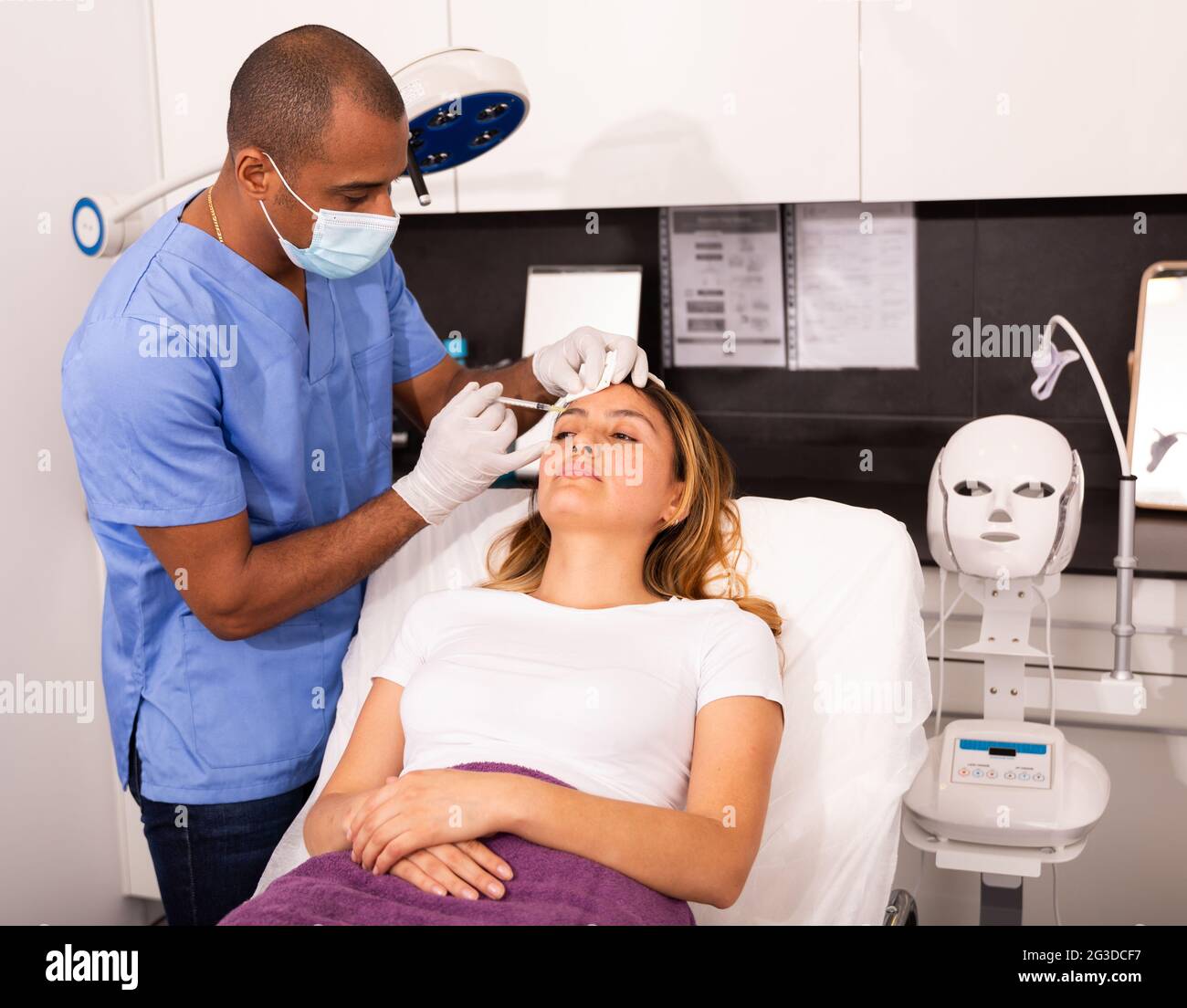 Male beautician performing face contouring injections to female Stock ...