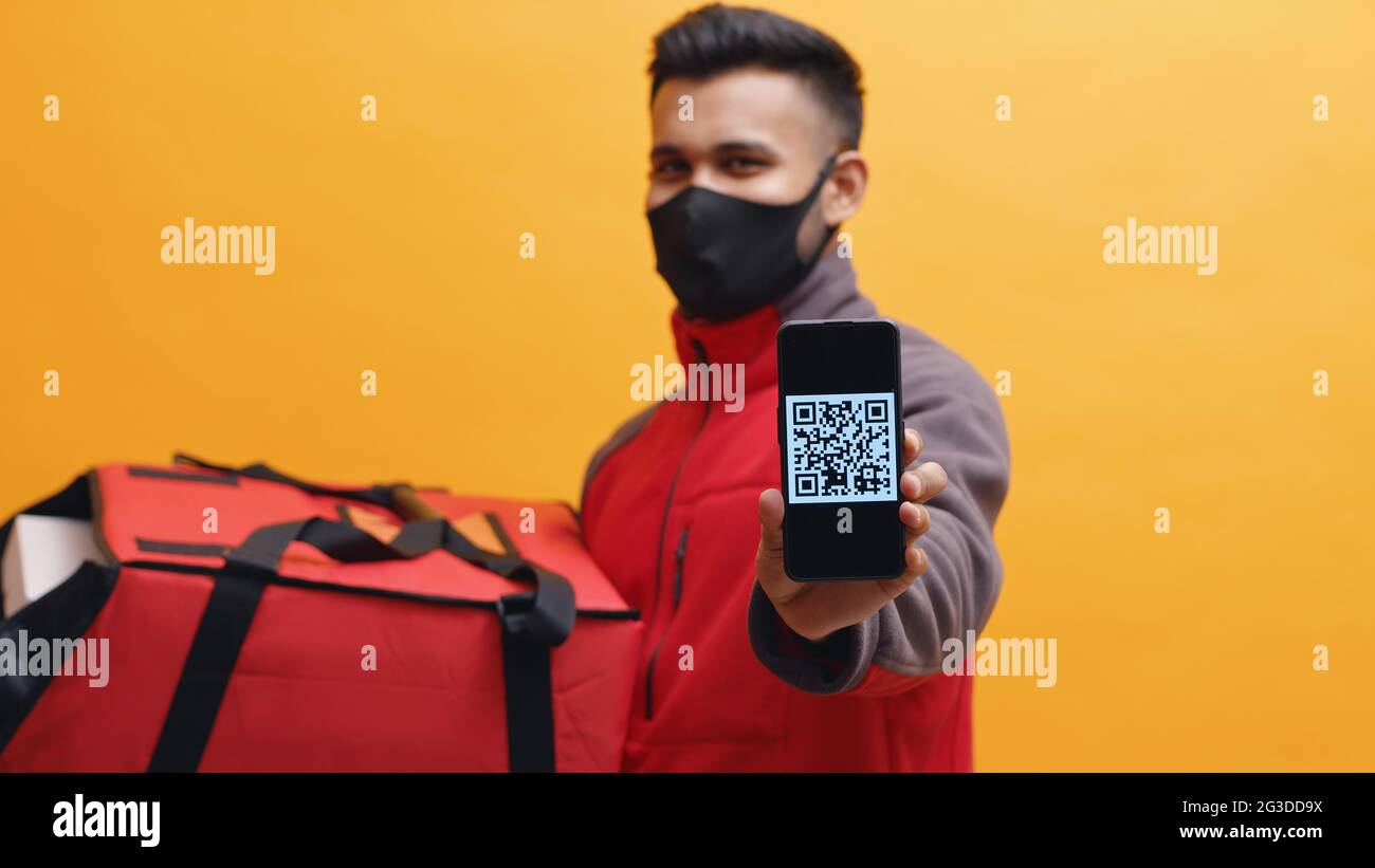 Delivery man wearing black mask holding red parcel box. Showing mobile ...