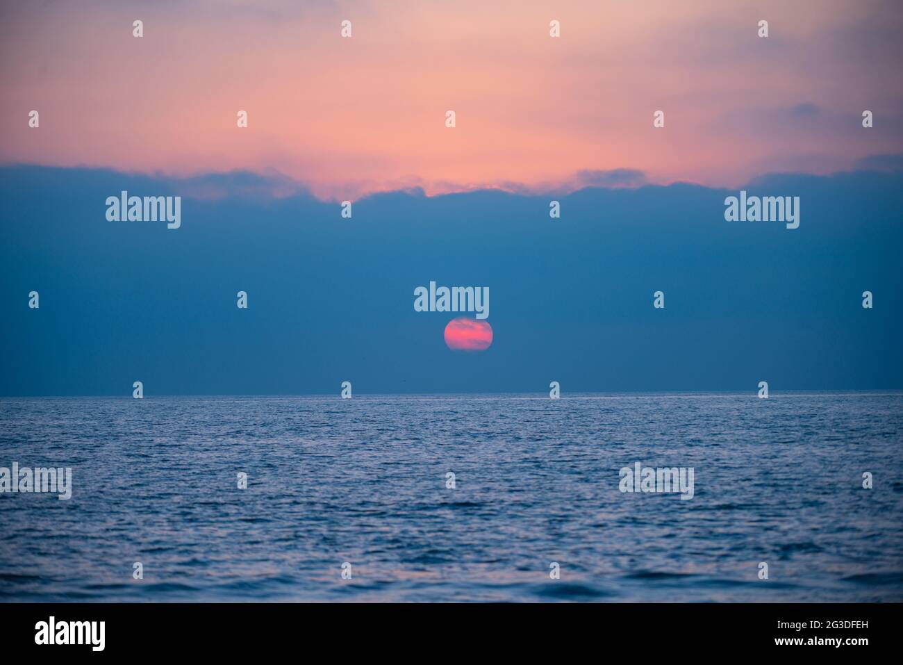 Calm sea with sunset sky and sun through the clouds over. Ocean and sky ...