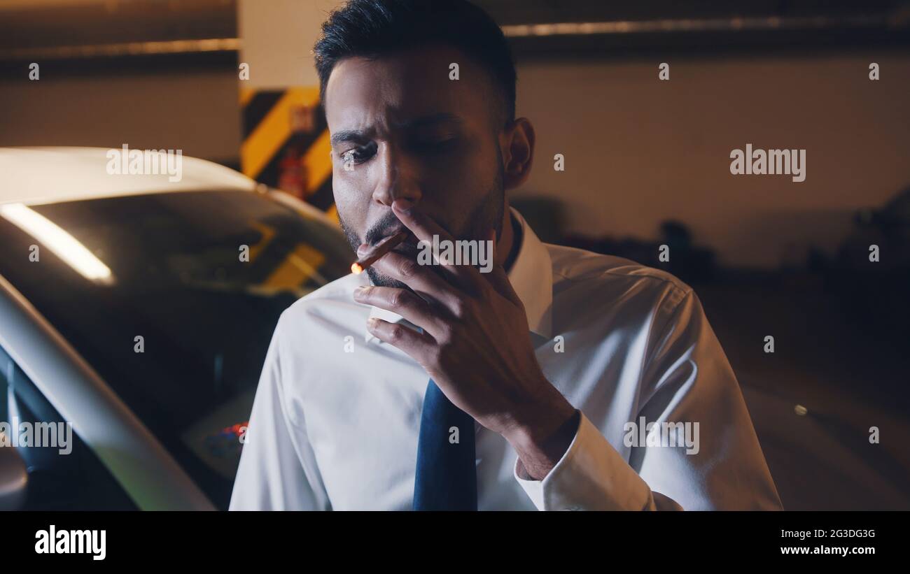 Young man in the parking lot smoking. Dressed in white shirt and tie ...