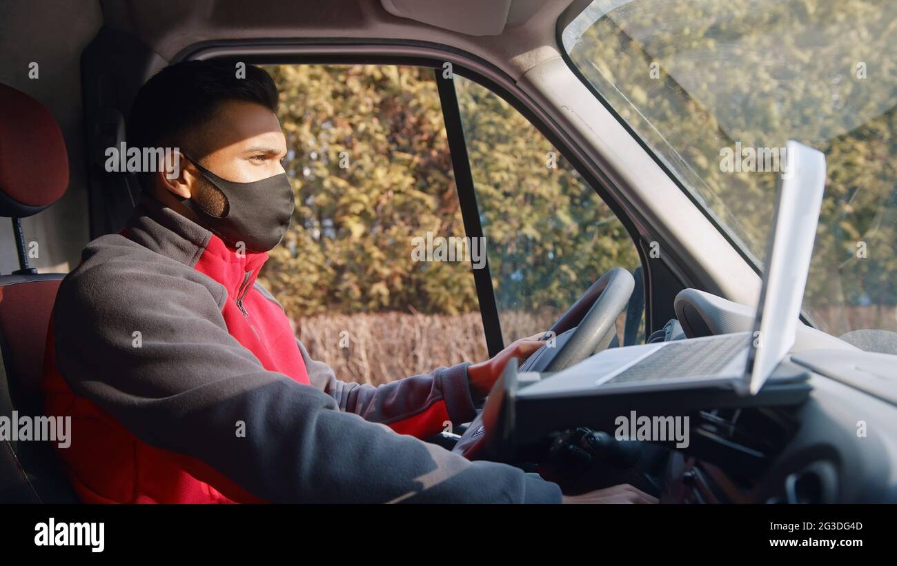 Young guy driving the car holding steering and gear. A laptop is placed ...
