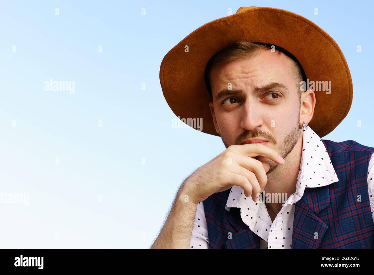 Portrait of a handsome young man in a hat against a blue sky. Caucasian ...