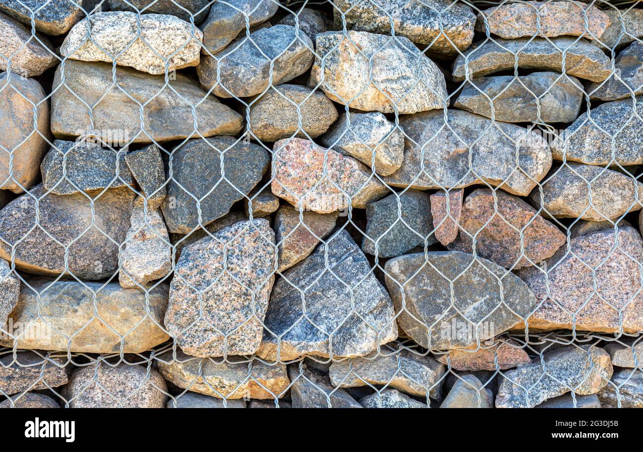 Stone wall with metal grid as background. Rock texture in metal grid ...