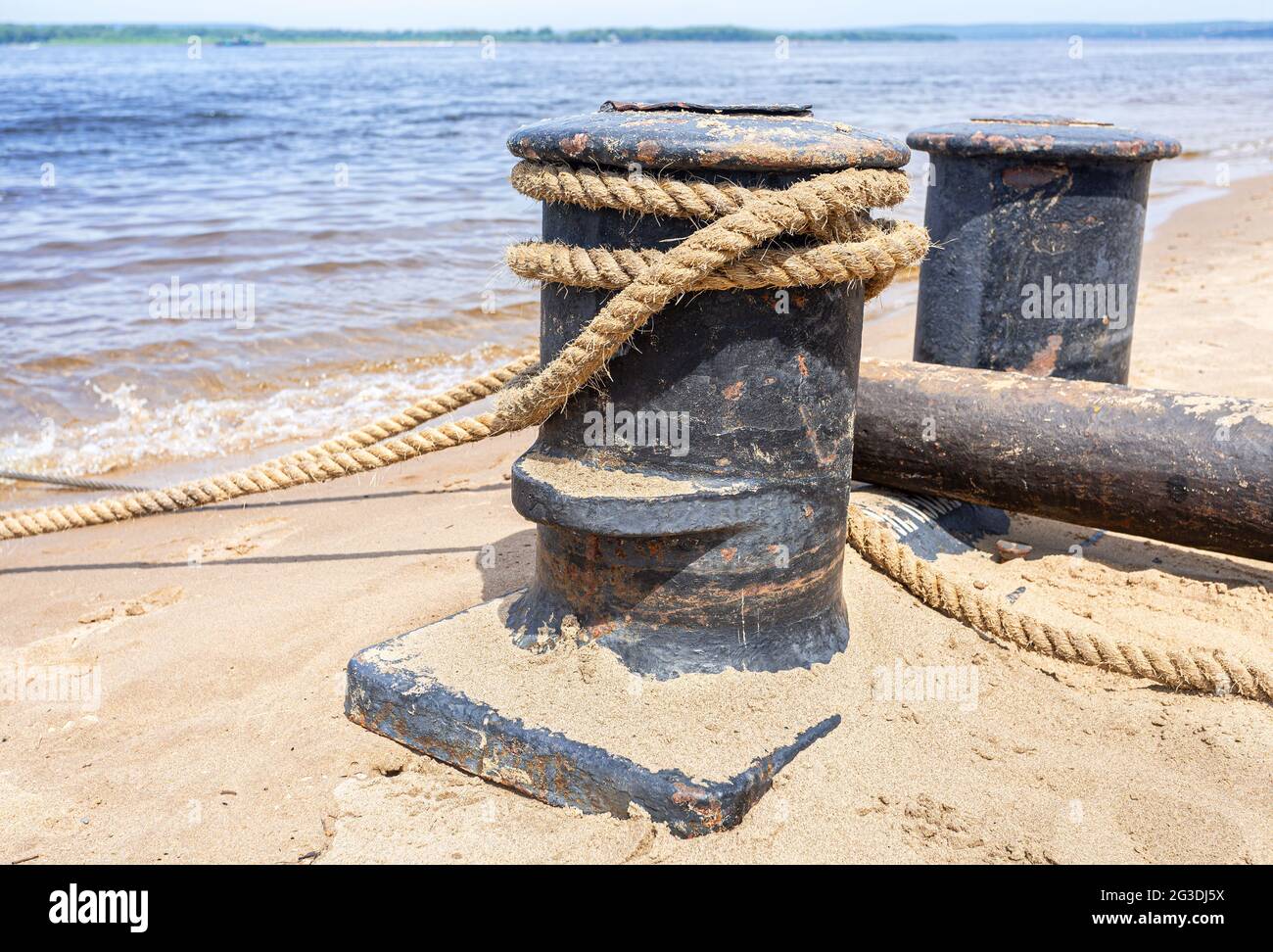 Mooring bollard with a fixed rope in the harbor on the sand beach Stock ...