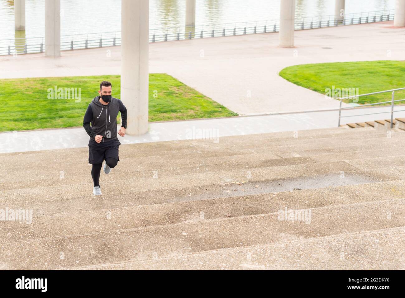 Runner climbing the stairs. Dressed in sportswear wearing a mask Stock ...