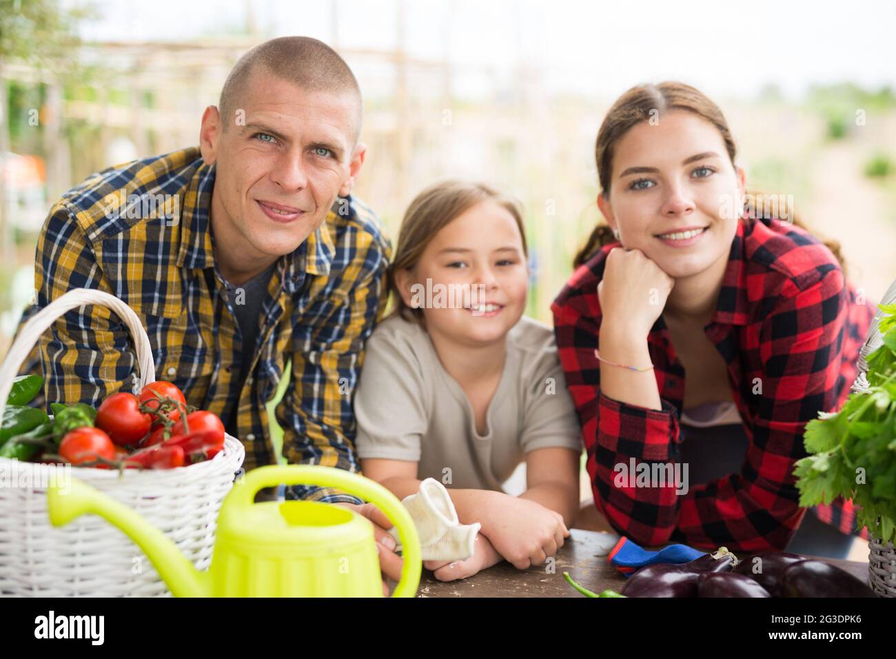 Happy family with a harvest of vegetables sits at table in the backyard ...