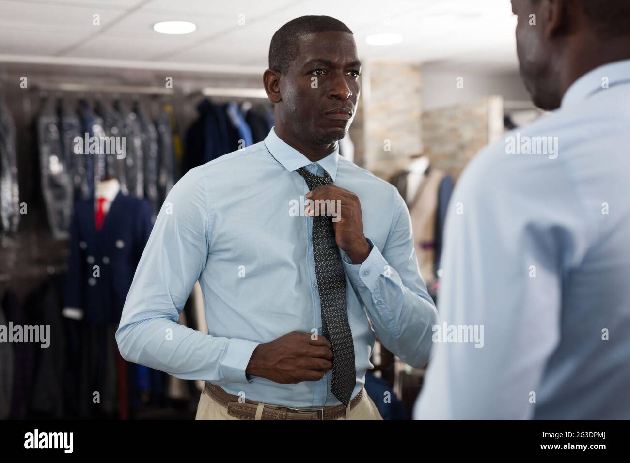 Confident male customer choosing fashion beige suit in mens store Stock ...