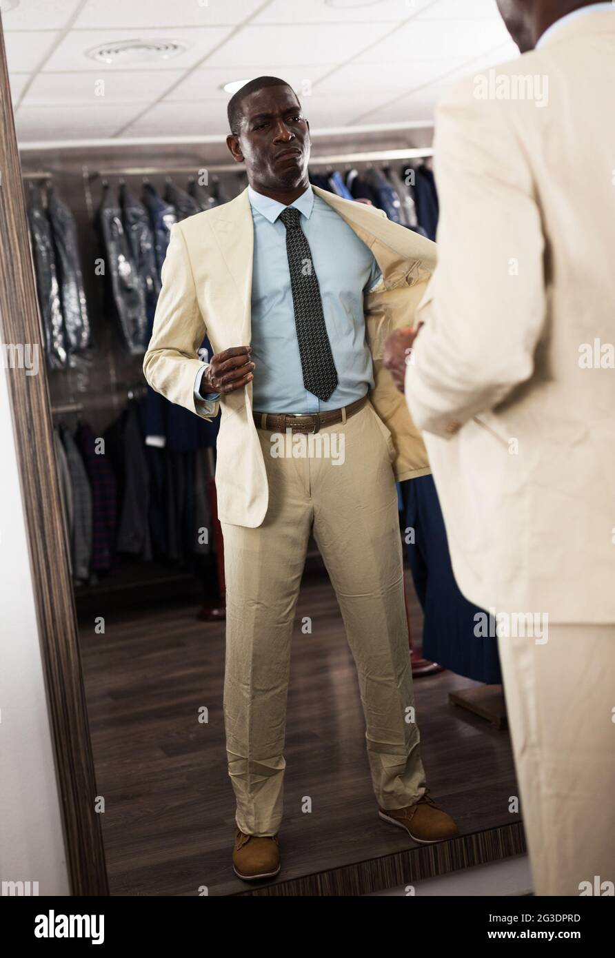 Confident male customer choosing fashion beige suit in mens store Stock ...