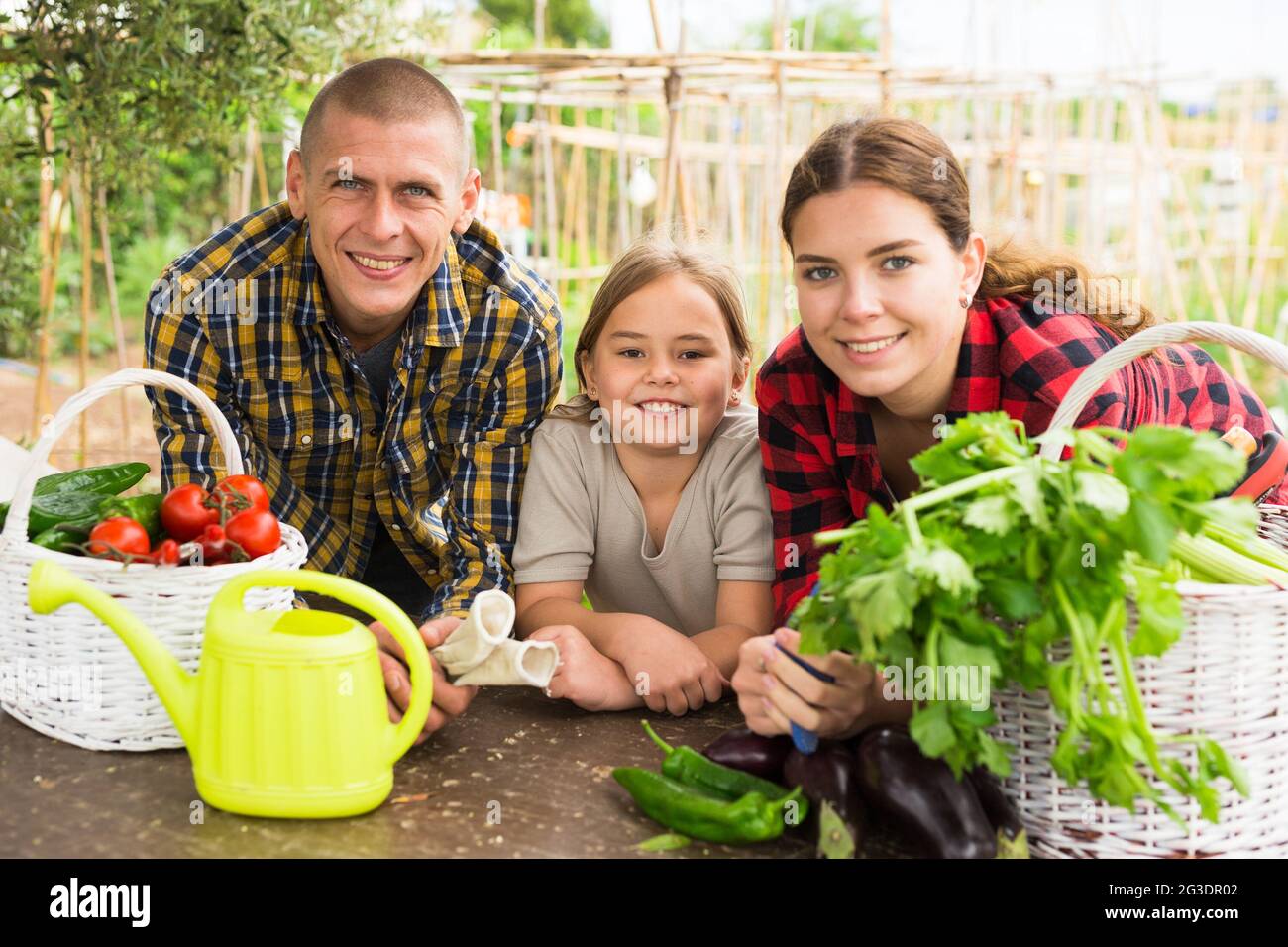 Happy family with a harvest of vegetables sits at table in the backyard ...