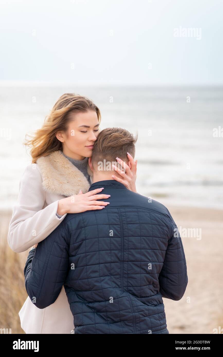young beautiful stylish couple in spring on the beach. Hug each other ...