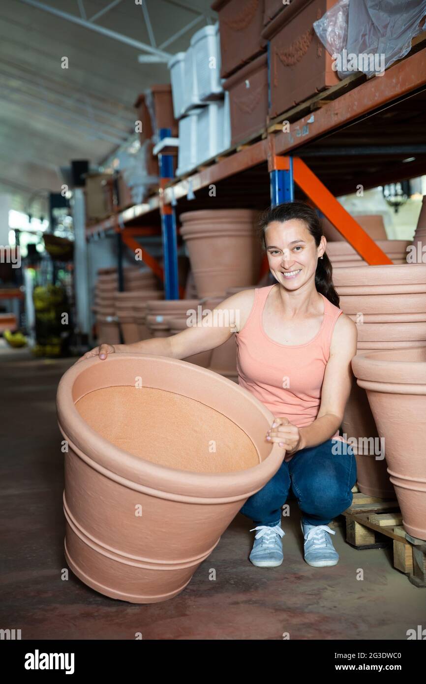 Young woman customer choosing big clay pot for garden Stock Photo - Alamy