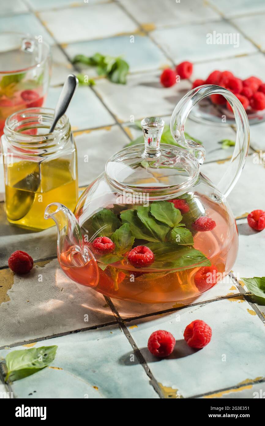 Hot raspberry tea in transparent teapot on a stone table. Fresh berries ...