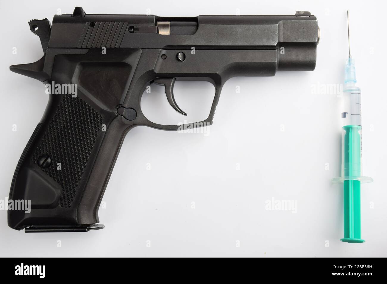 The black gun lies with a plastic syringe and a needle on a white ...