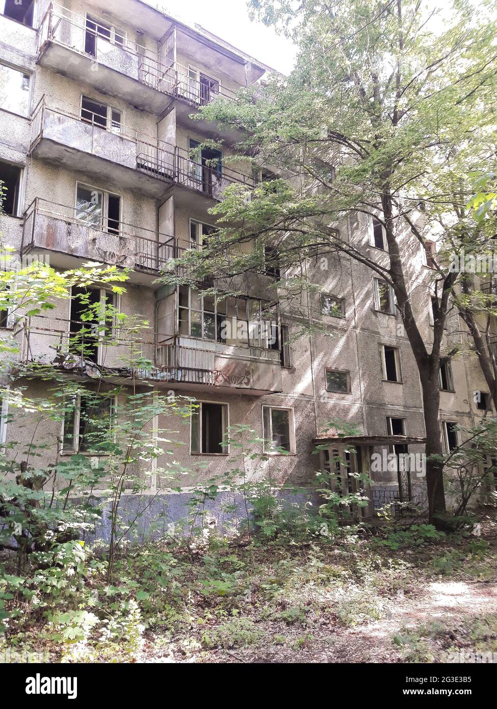 Abandoned overgrown high-rise building with balconies and front door ...