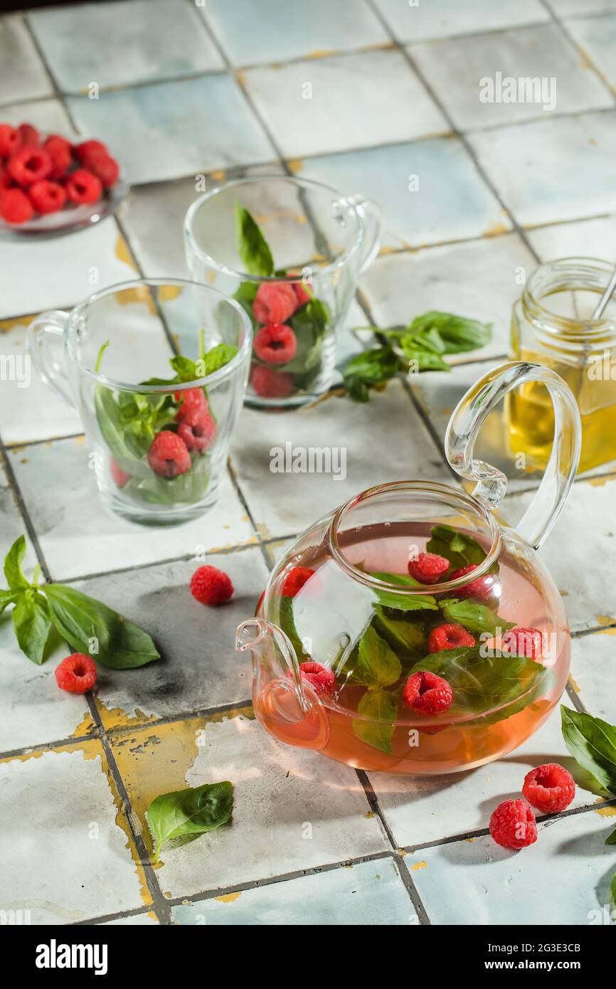 Hot raspberry tea in transparent teapot on a stone table. Fresh berries ...