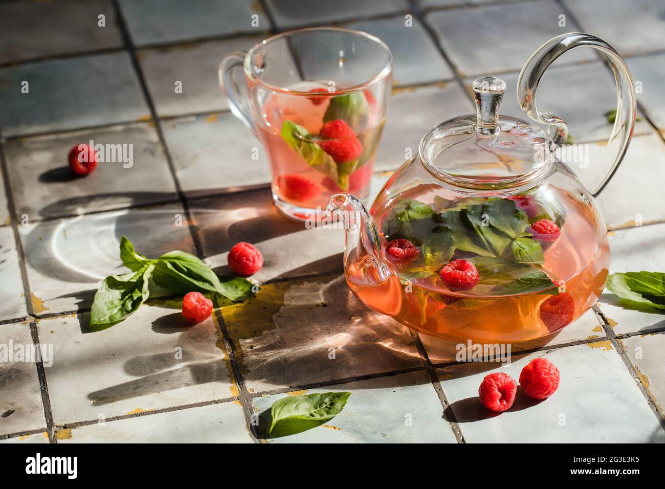 Hot raspberry tea in transparent teapot on a stone table. Fresh berries ...
