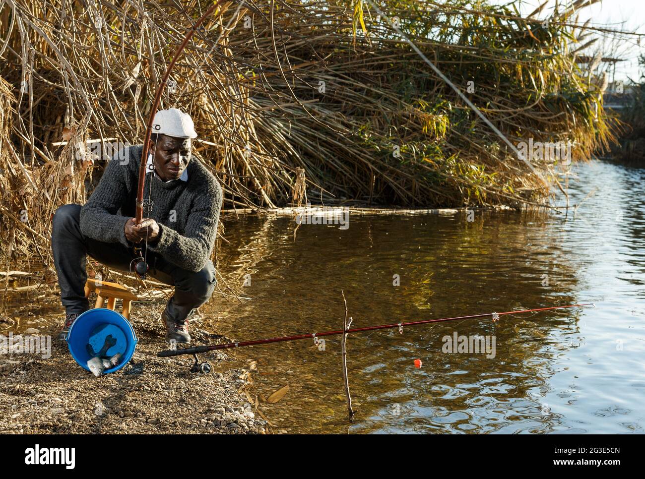 Mature African man pulling fish Stock Photo - Alamy