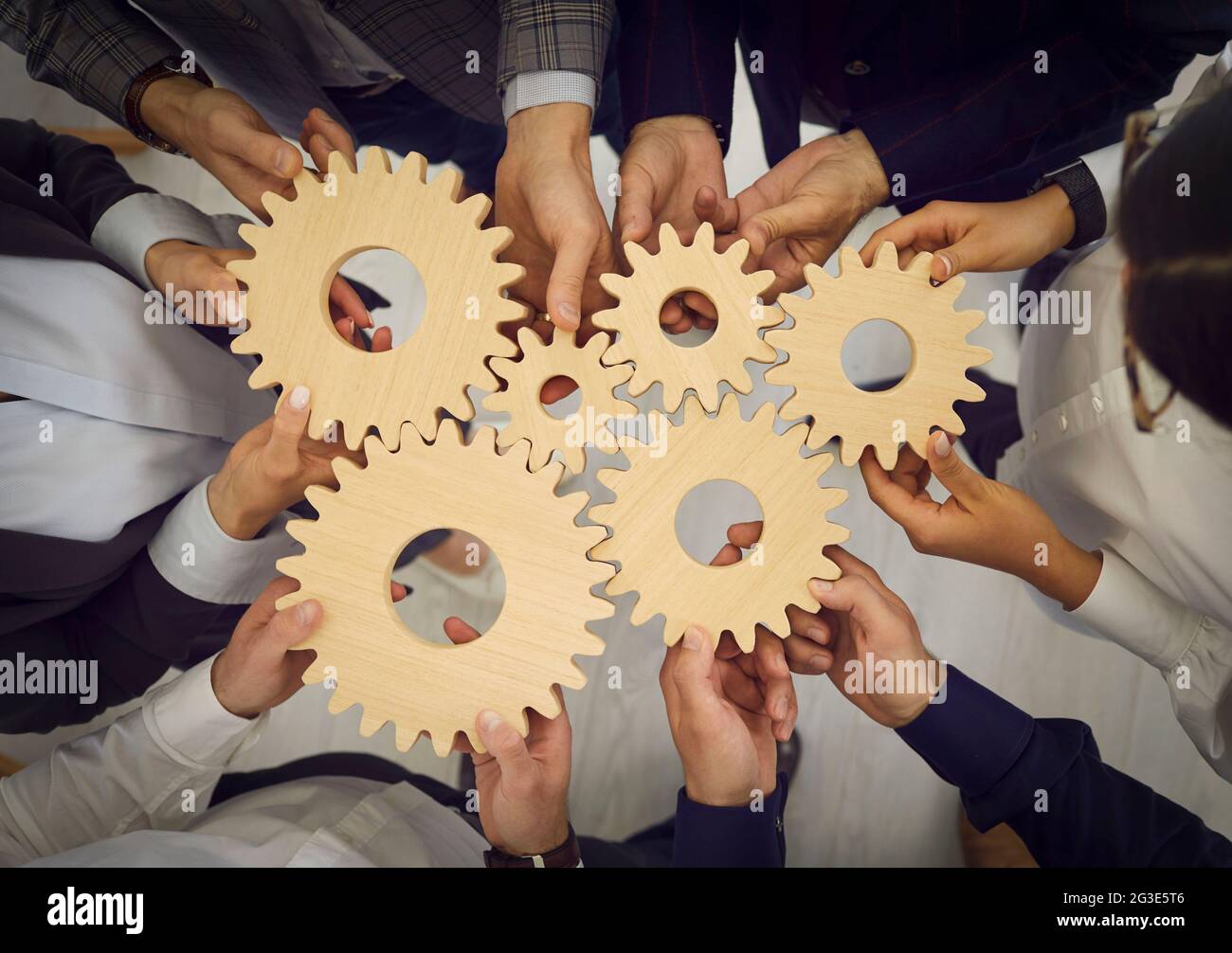 Group of business people join cogwheels as metaphor for teamwork and ...