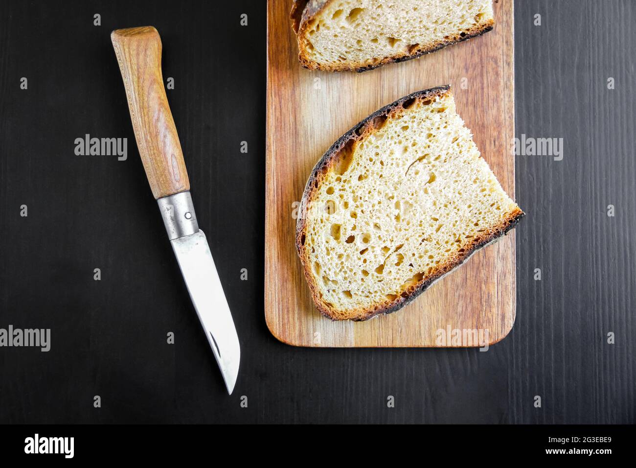 Traditional French country bread slices and pocket knife on a wooden ...