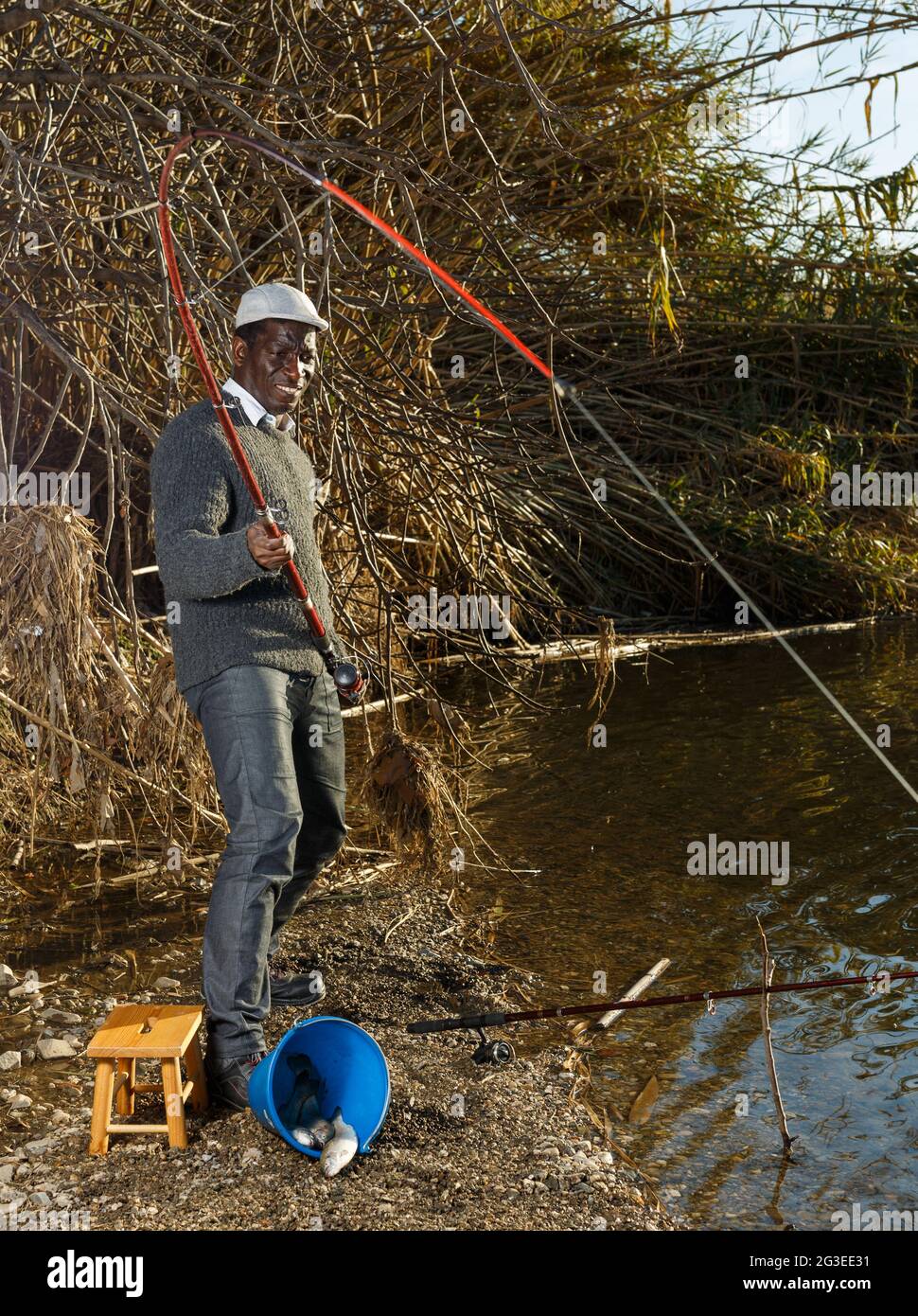 Afro fisherman pulling fish Stock Photo - Alamy