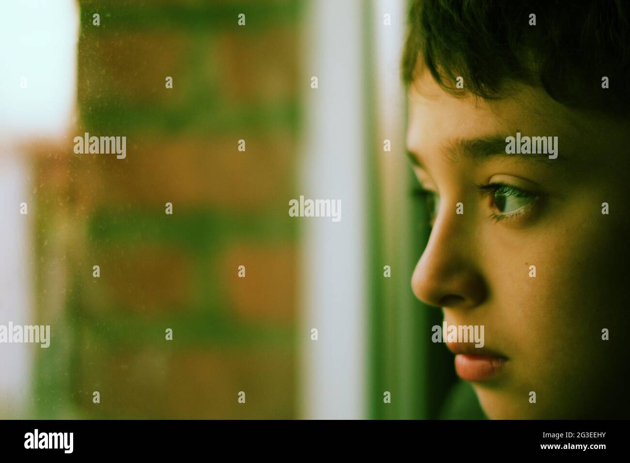 Cute young boy looking through window split toning Stock Photo - Alamy