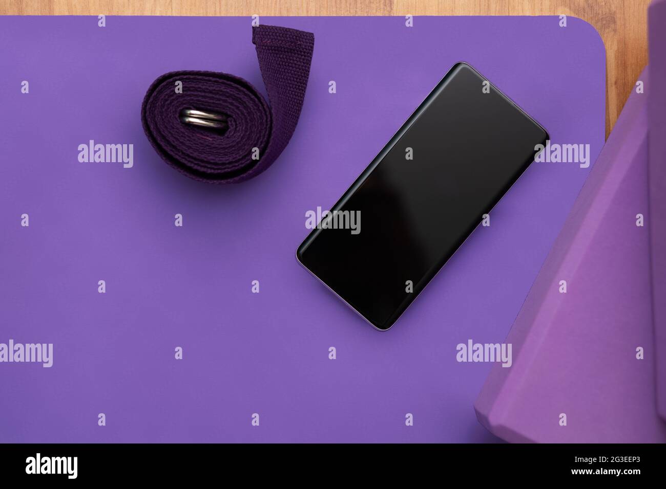 Blank phone on purple yoga mat with blocks and strap. Top view. Health ...