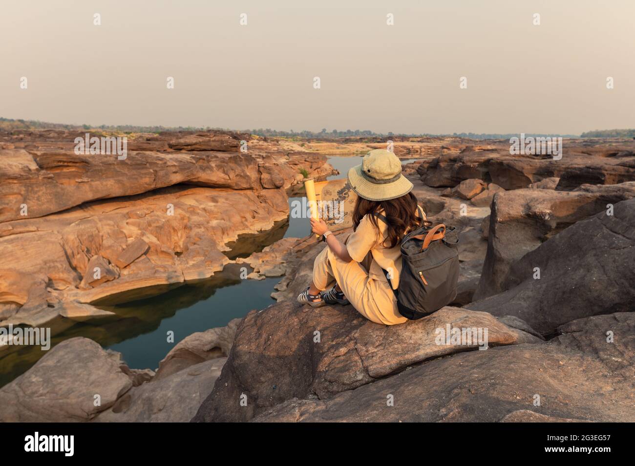 Explorer asian woman sitting on rock cliff with looking at paper map in ...