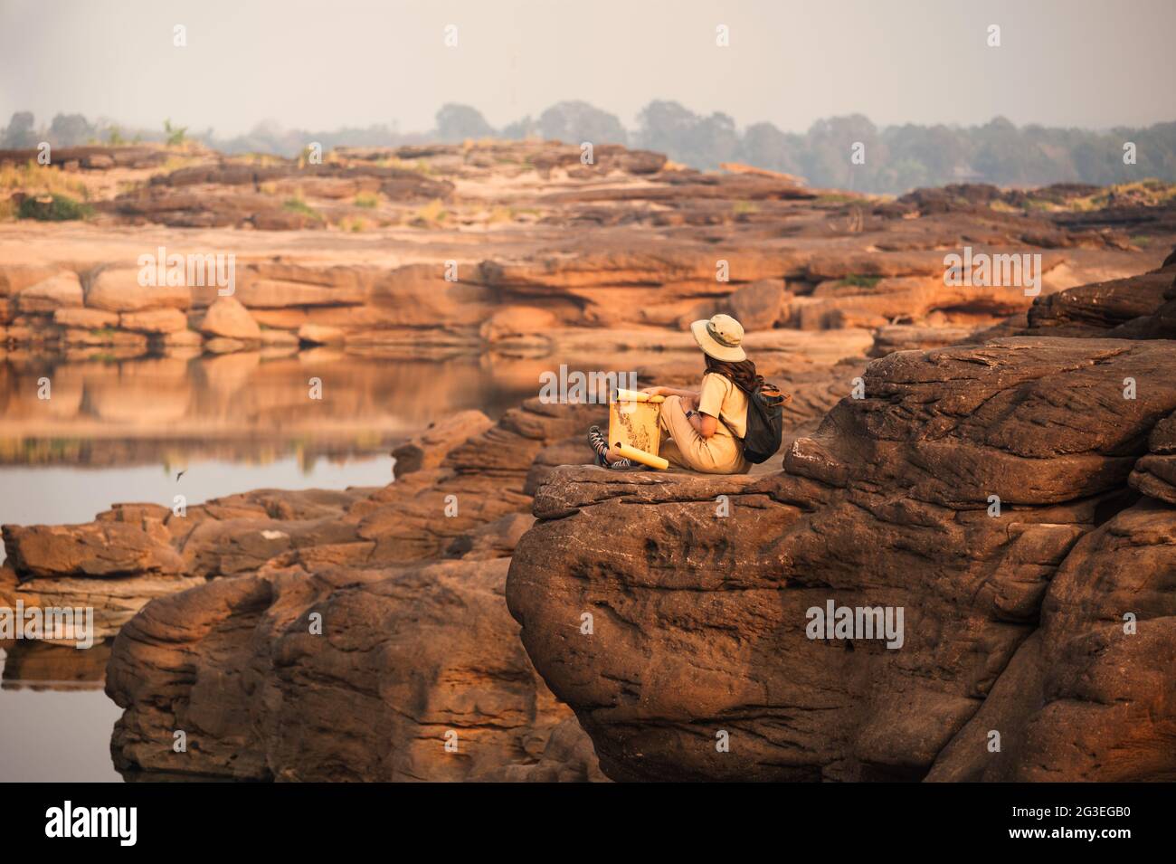 Asian woman explorer sitting on rock cliff with looking at paper map in ...