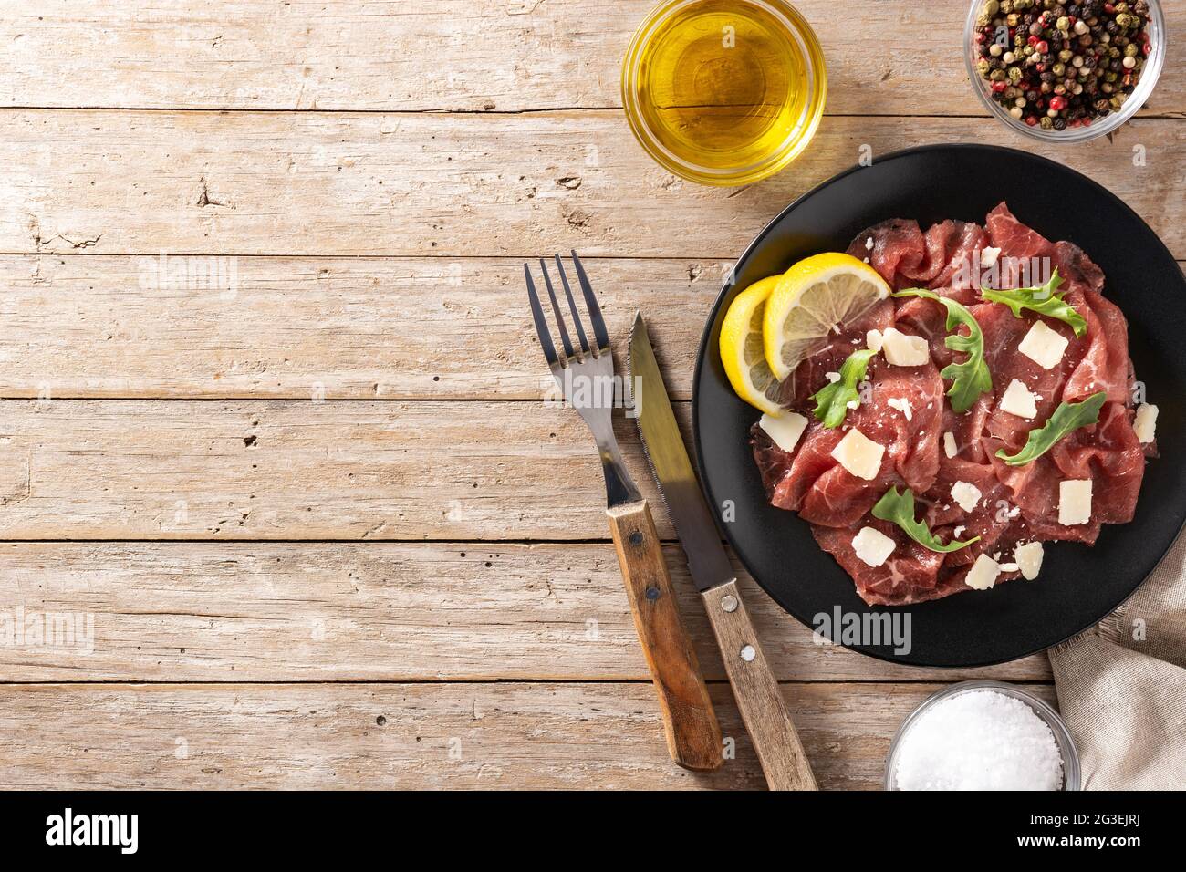 Marbled beef carpaccio on black plate and rustic wooden table Stock ...