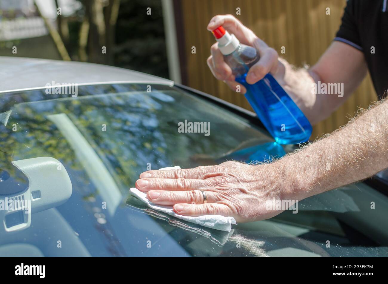 Man cleaning a car windshield with glass cleaning agent Stock Photo - Alamy