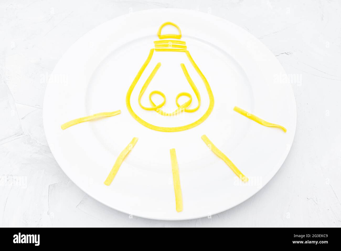 Glowing light bulb symbol made from boiled pasta on a white plate on a ...