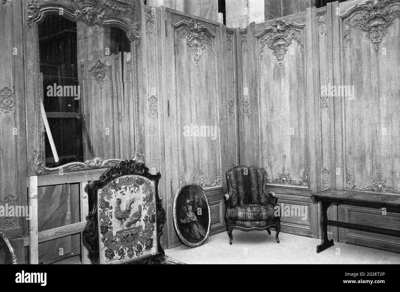 Paneling with fireplace, oval painting, table and armchair; Trial ...