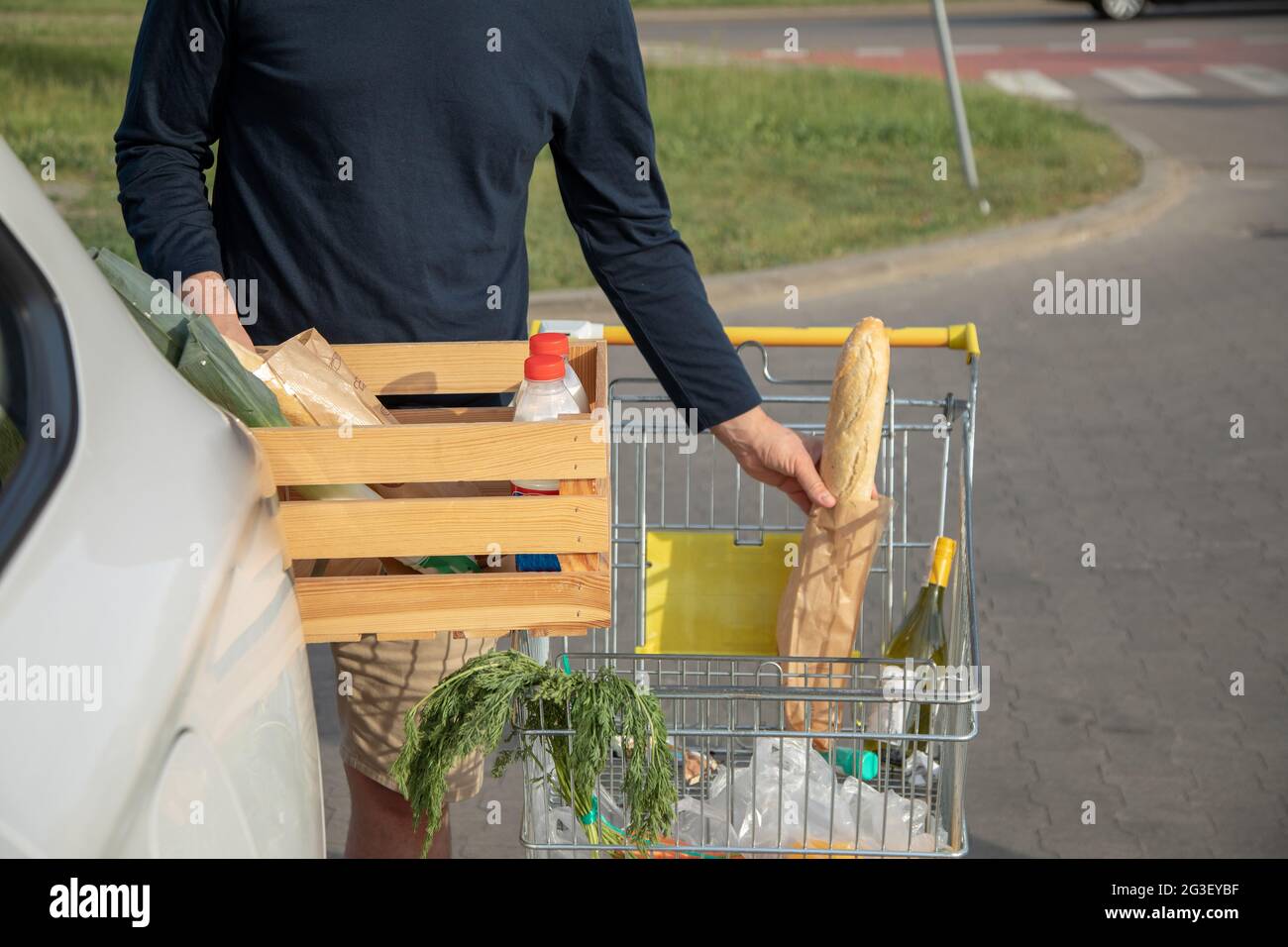 Man unloads food from cart intocar.Eco-friendly use of packaging. Close ...