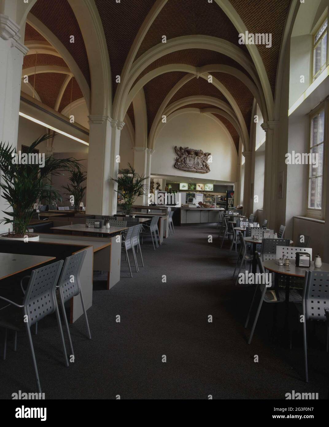 Public restaurant with square and round tables, plants and a cash ...