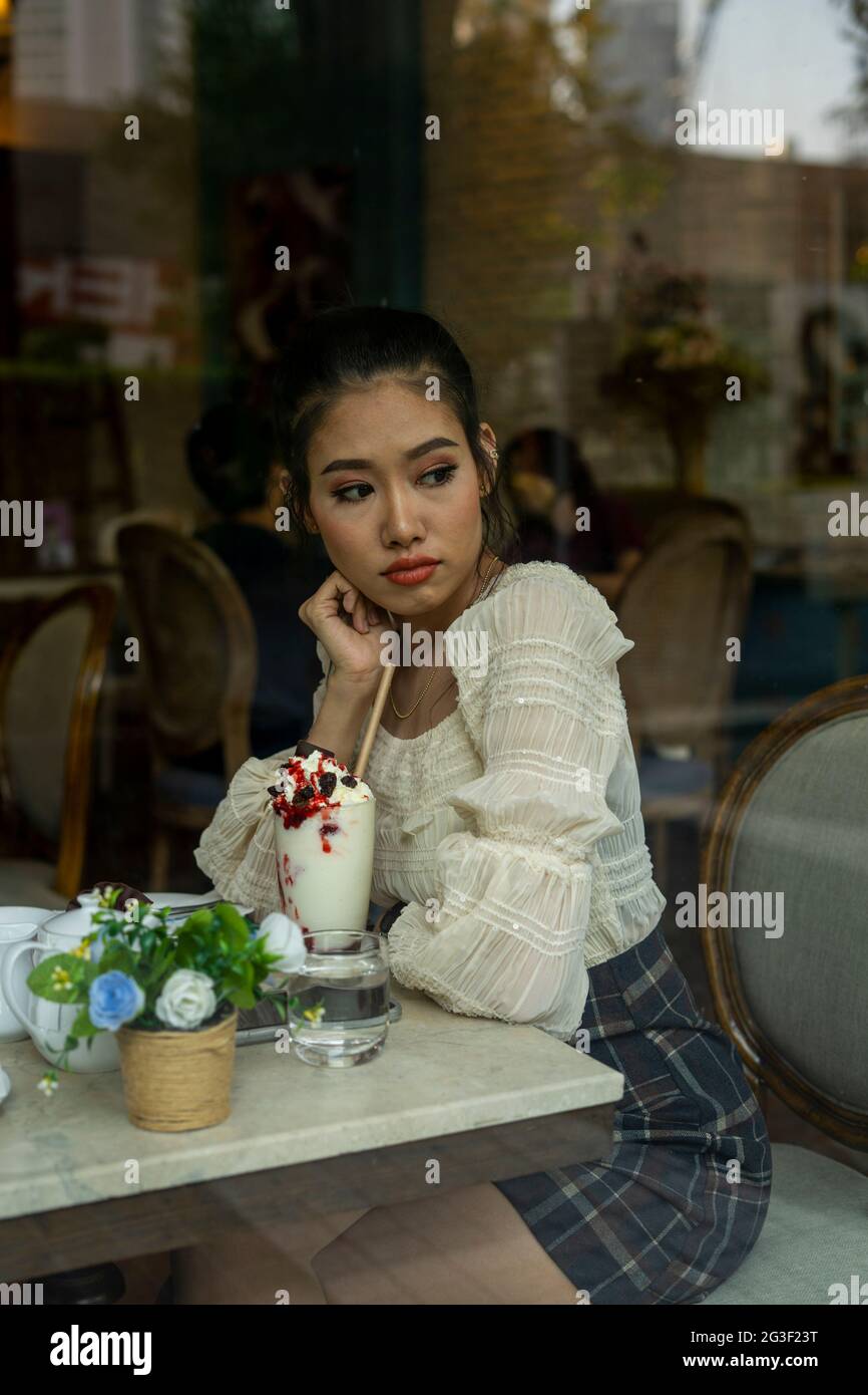 Very pretty dark hair asian girl posing in café window Stock Photo - Alamy