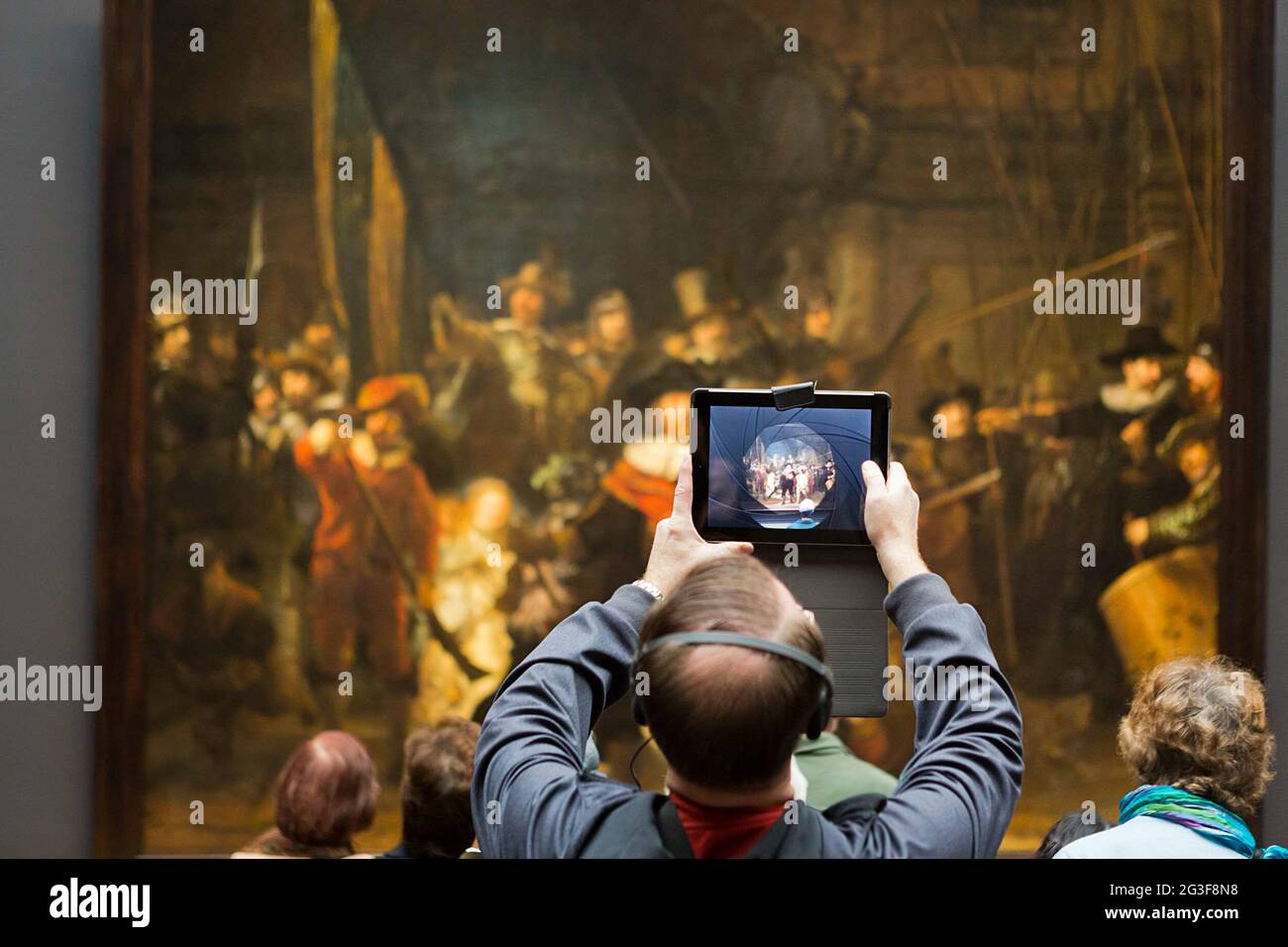 Museum visitor with an audio tour takes a photo with a night watch ...