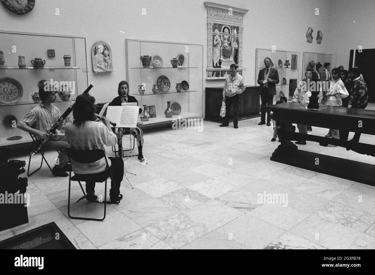 Two sitting women and a man playing wind instruments while public ...