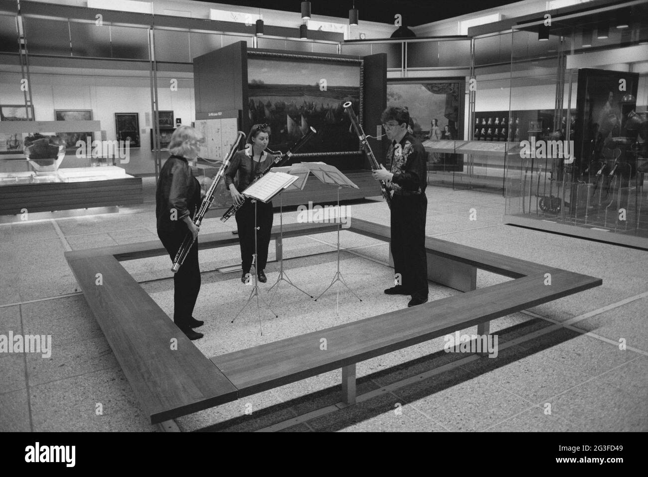 Two standing women and a man playing bladder instruments in a square ...