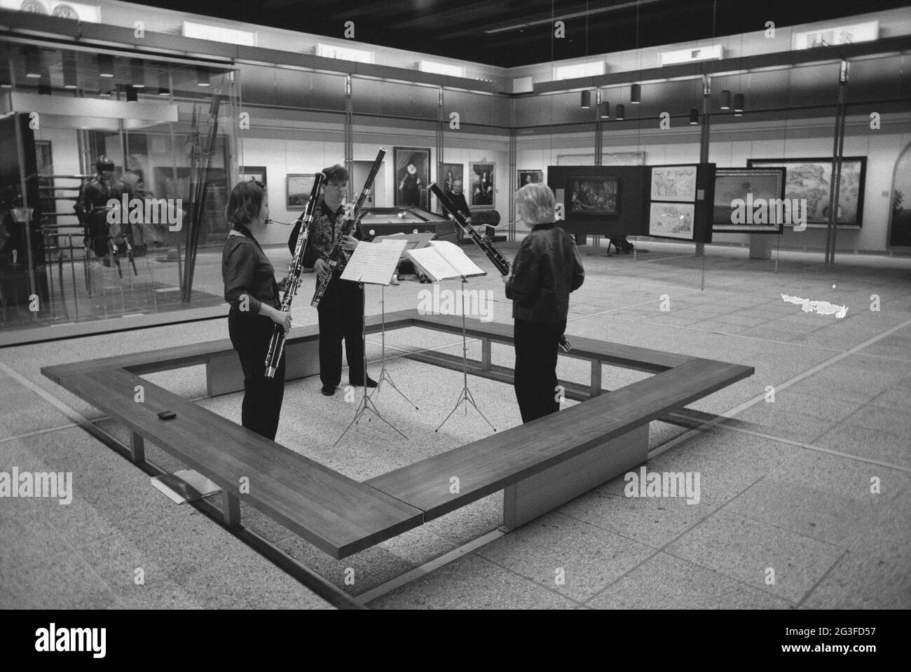 Two standing women and a man playing bladder instruments in a square ...