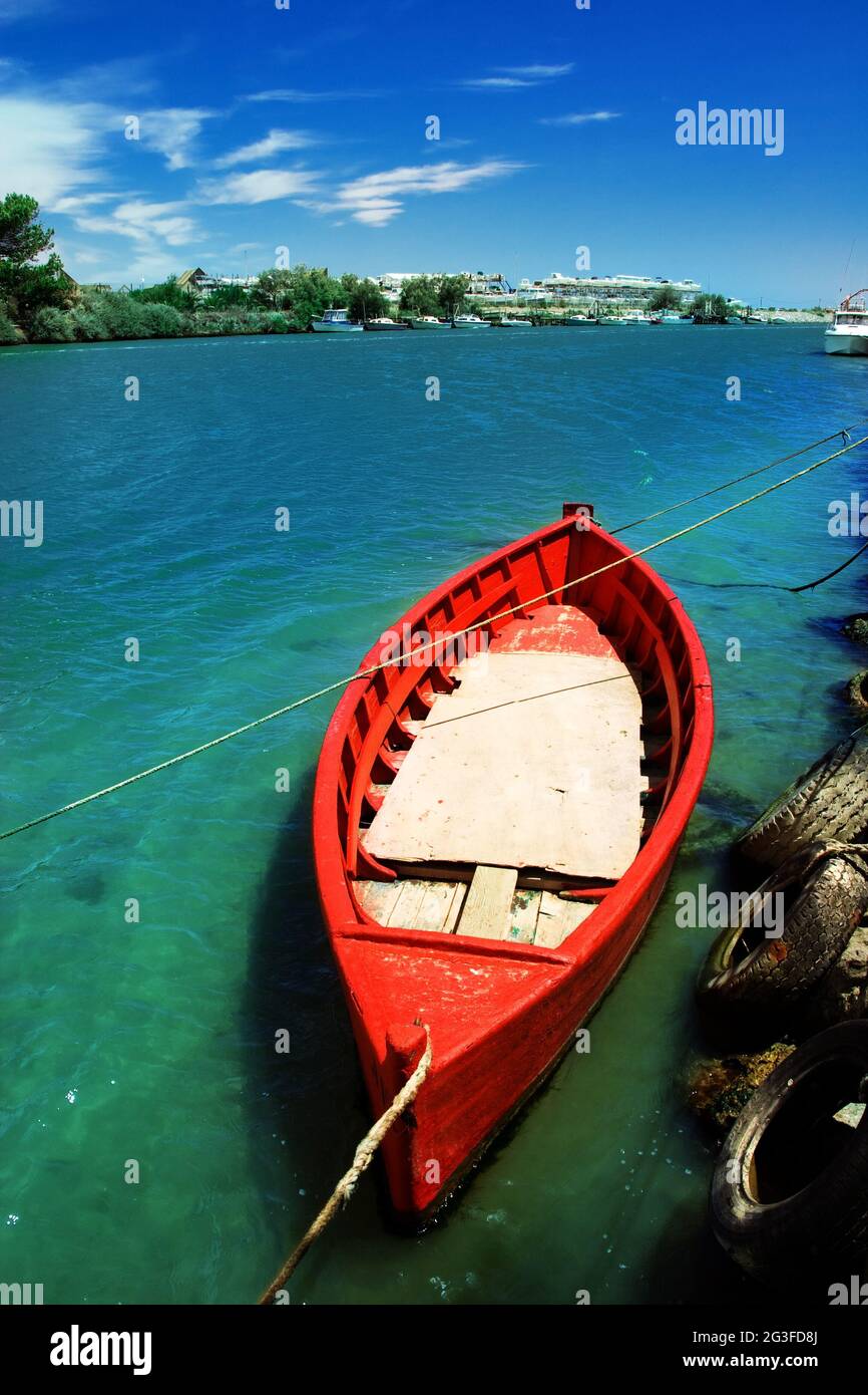 Red fishing boat on blue water Stock Photo - Alamy