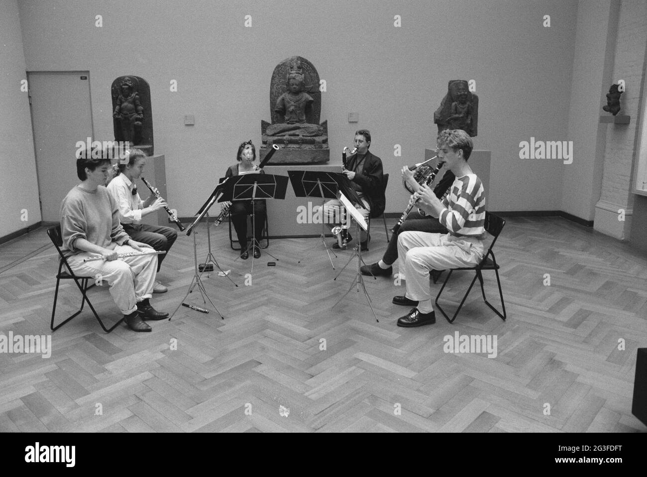 Sitting musicians playing wind instruments, behind them are images ...
