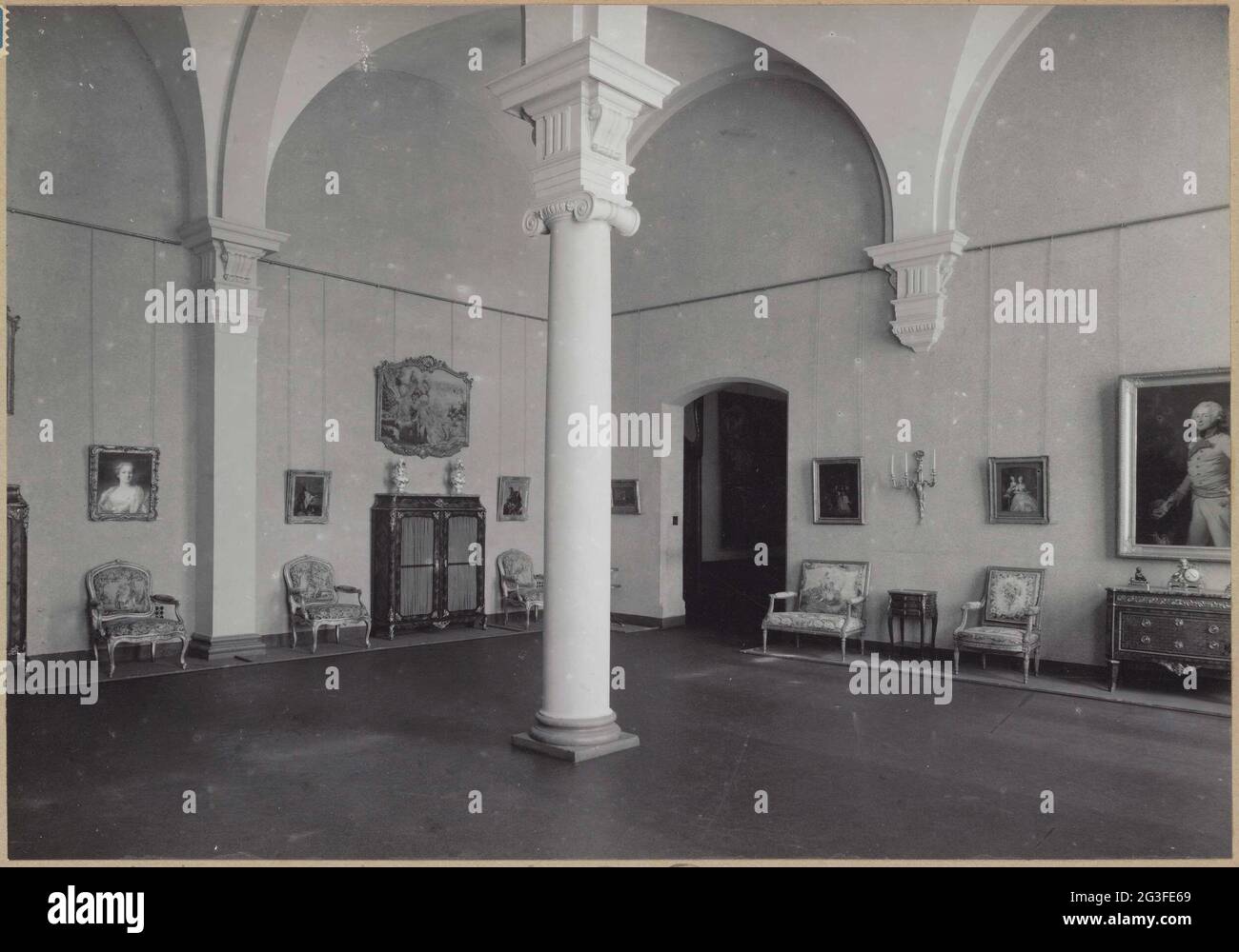 Room with paintings, cupboards, chairs and a passage in the middle ...