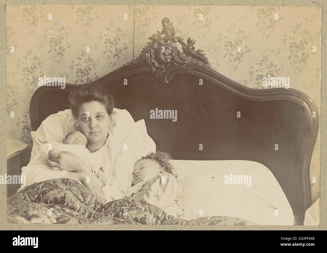 Mother with a baby and a child in a maternity bed. Part of photo album ...