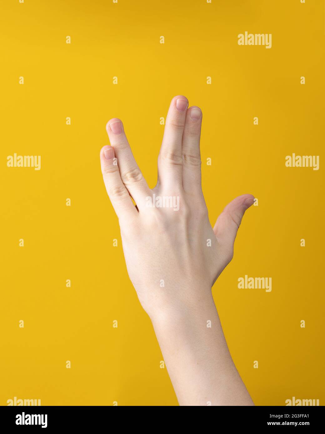 woman hand shows Vulcan salute on yellow background. Hand gesture that ...